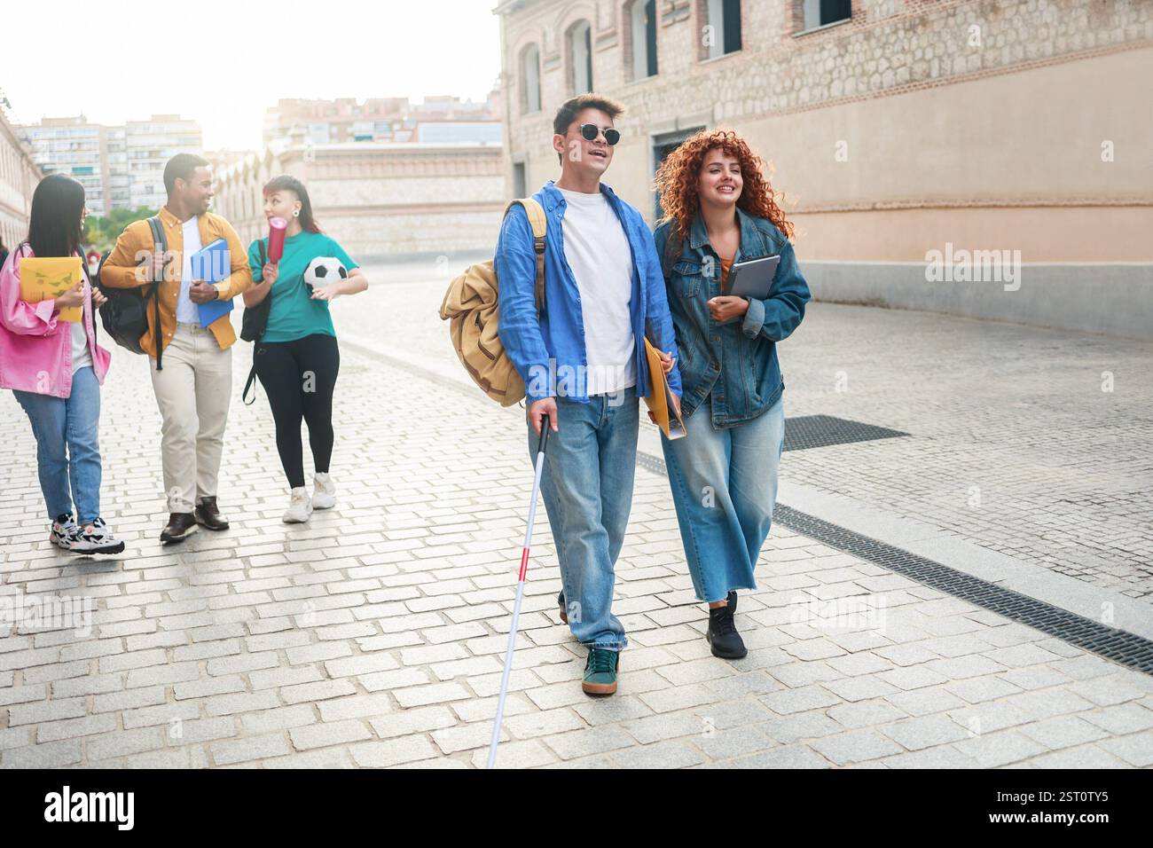 Happy blind man walks with group of friends inside school or university ...