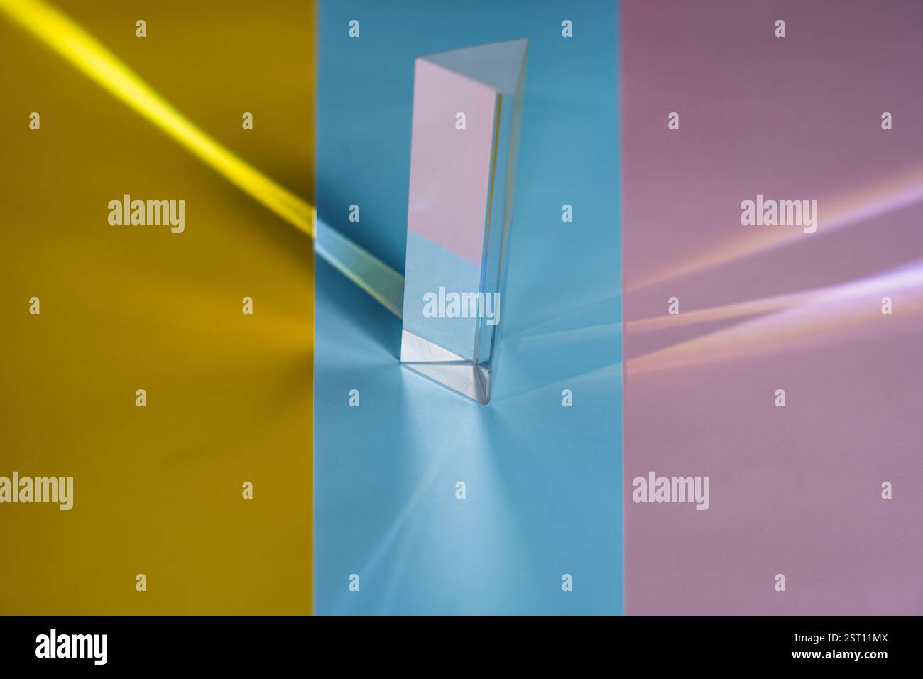 Transparent glass prism placed on yellow, blue, and pink paper ...