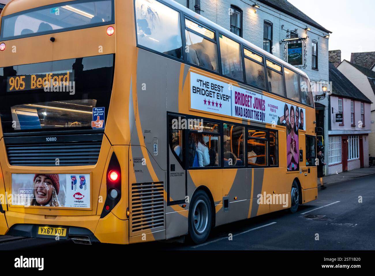 An advert-covered double-decker bus is seen traveling in Cambridge, UK ...