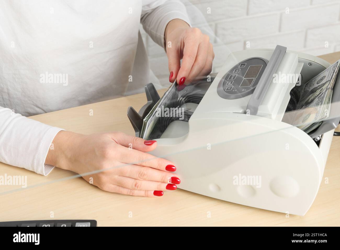 Cashier using money counting machine at table in currency exchange ...