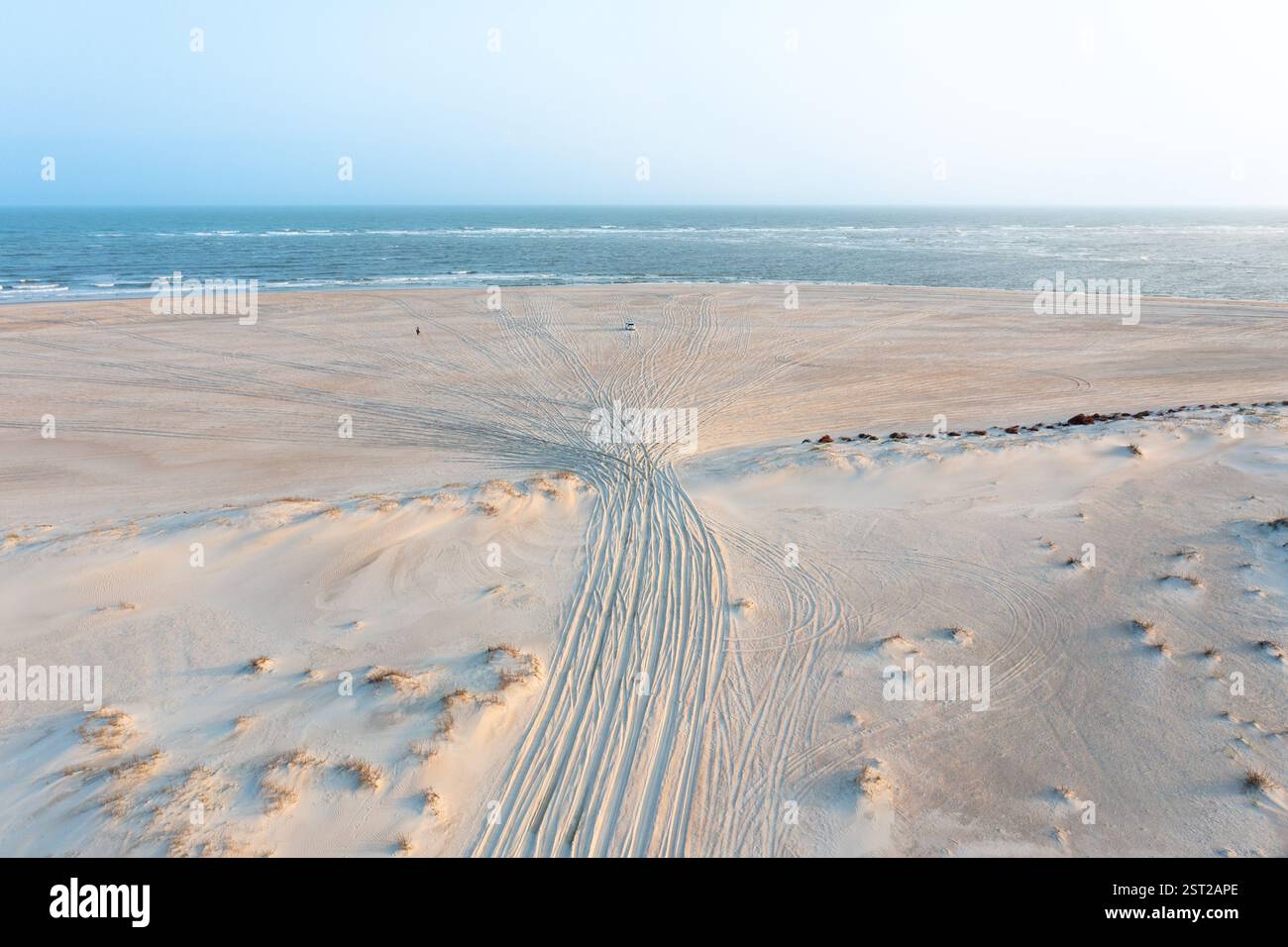 Aerial view of tire tracks in the sand leading out to the beach and ...