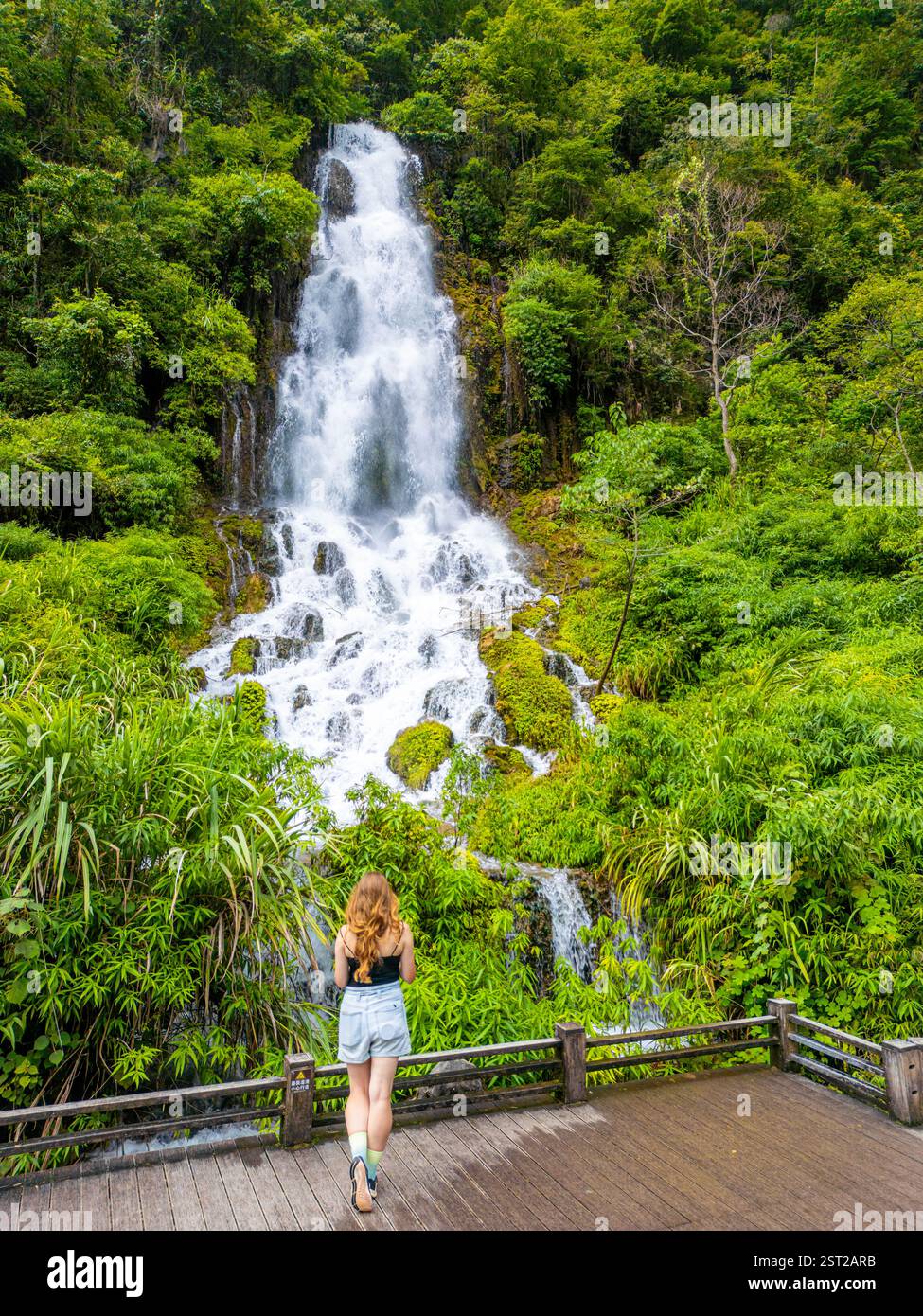 A girl standing next to Tall waterfall in Xiaoqikong scenic spot, Libo ...