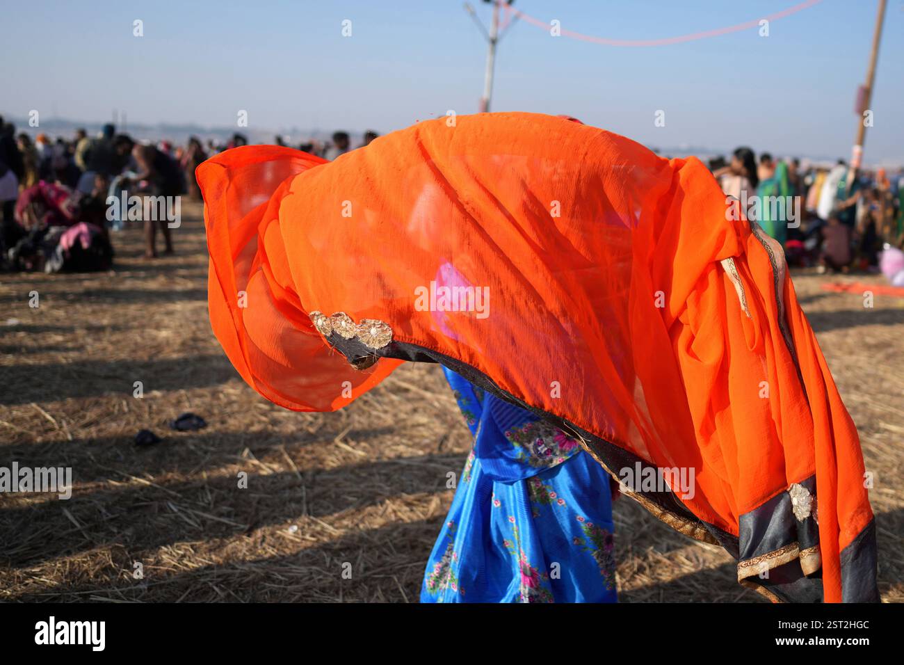 A pilgrim holds up her sari to dry after a holy dip at the confluence ...