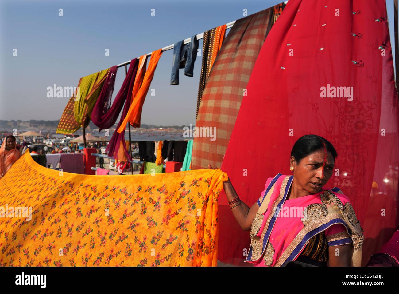Pilgrims hold up their saris to dry after a holy dip at the confluence ...