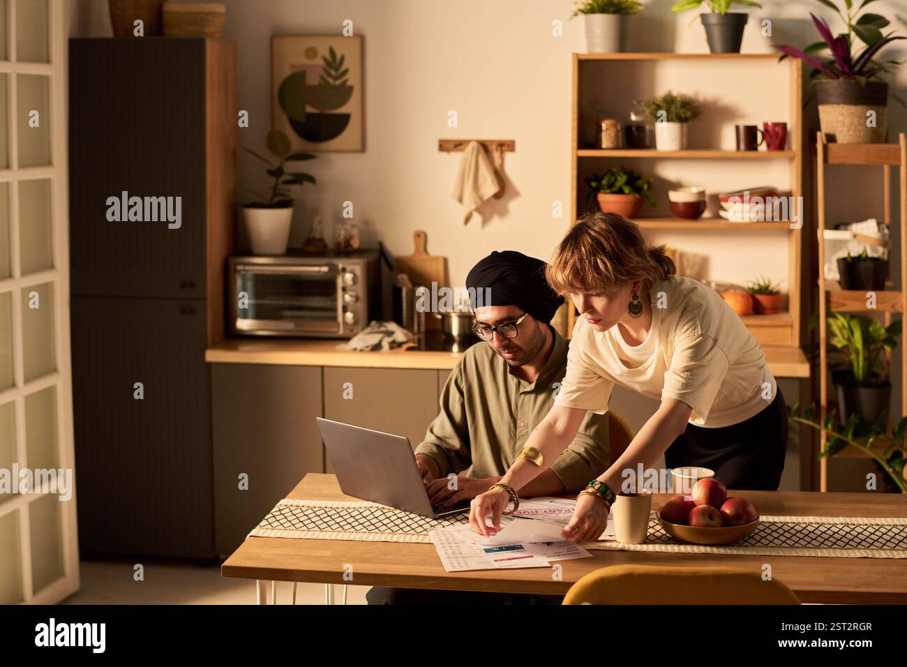 Two colleagues working at a kitchen counter, discussing documents and ...