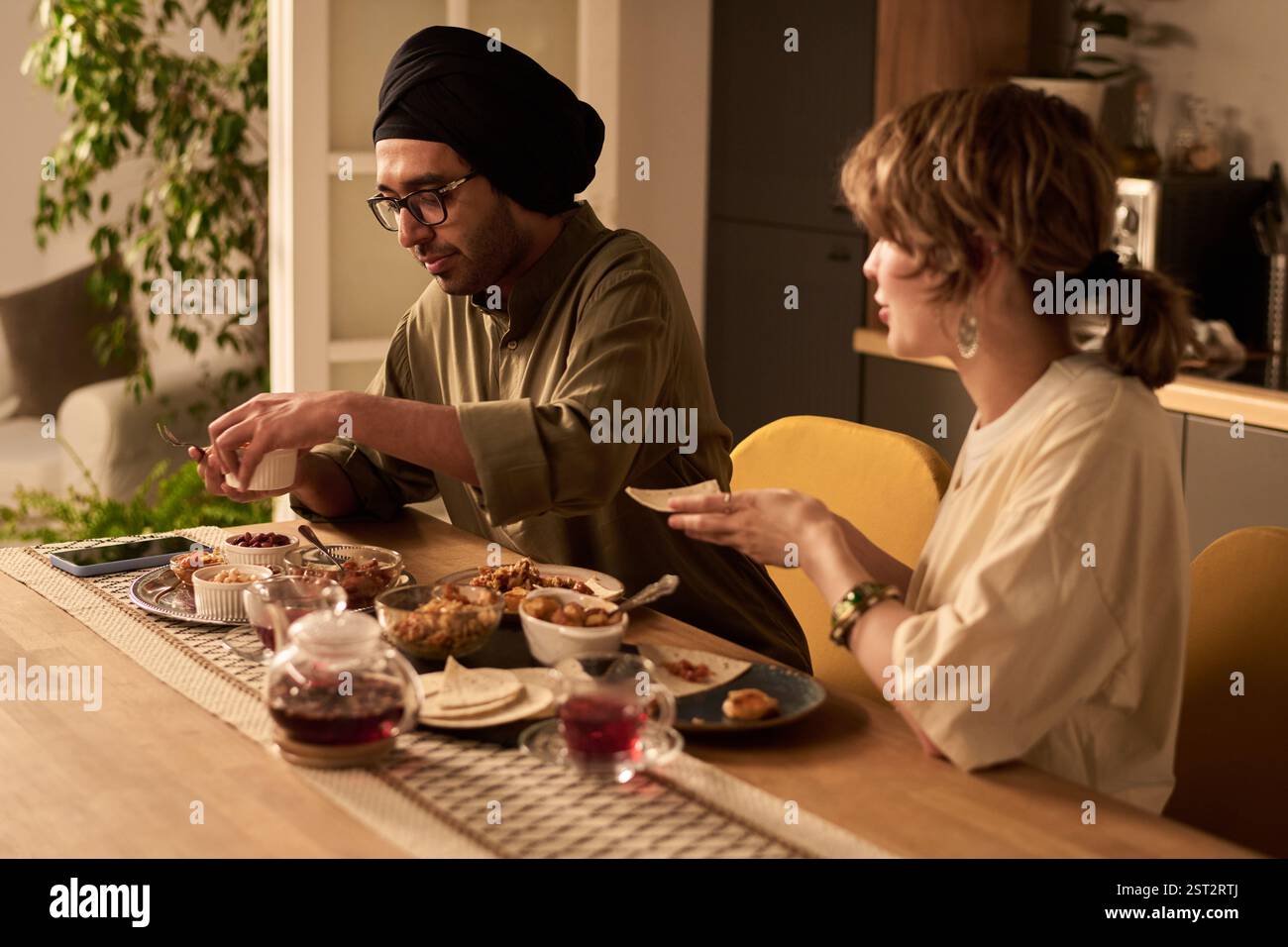 Two people sitting at dining table, savoring an array of Asian dishes ...