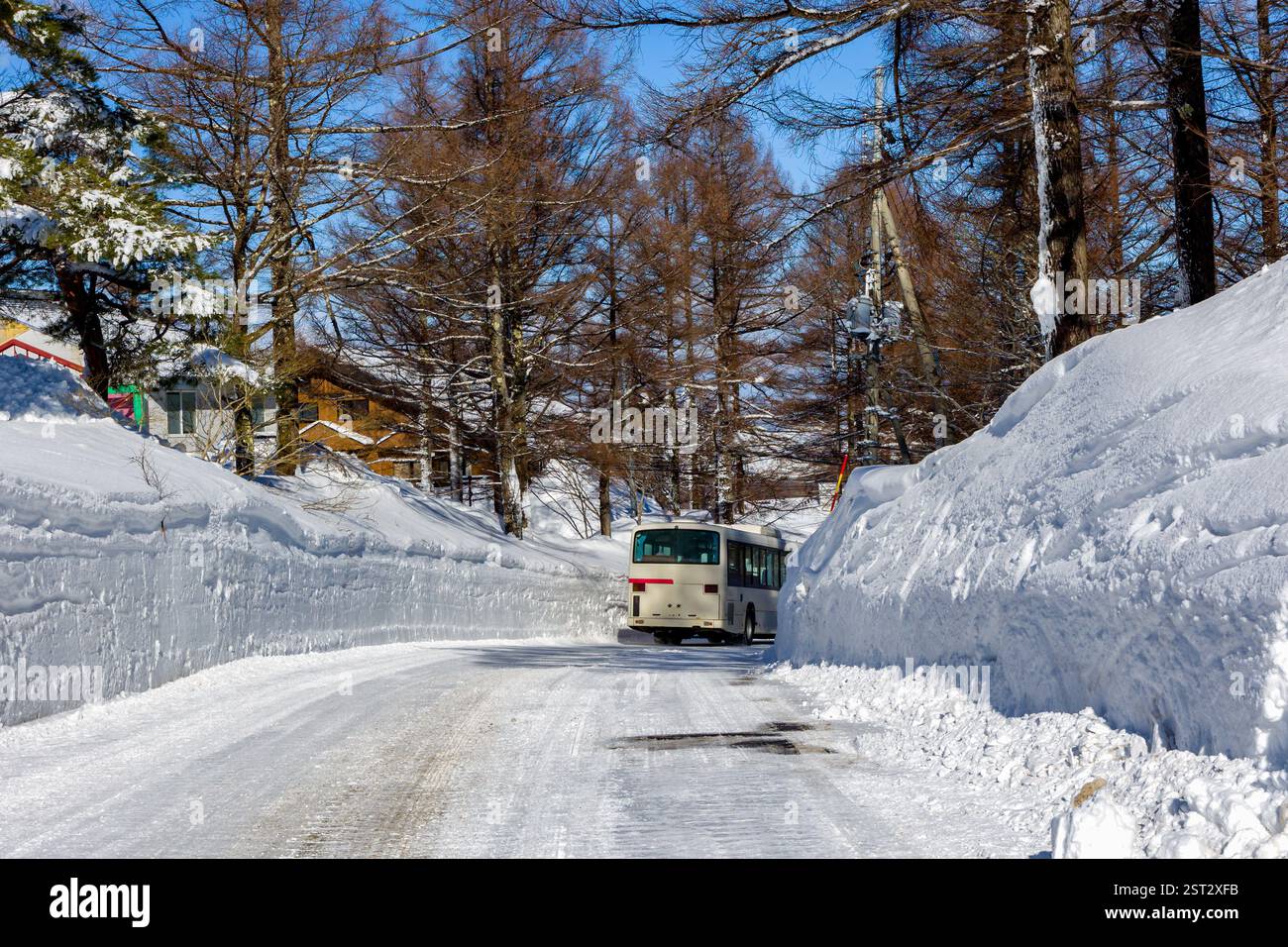 Tourist bus making its way through large piles of snow by the side of ...