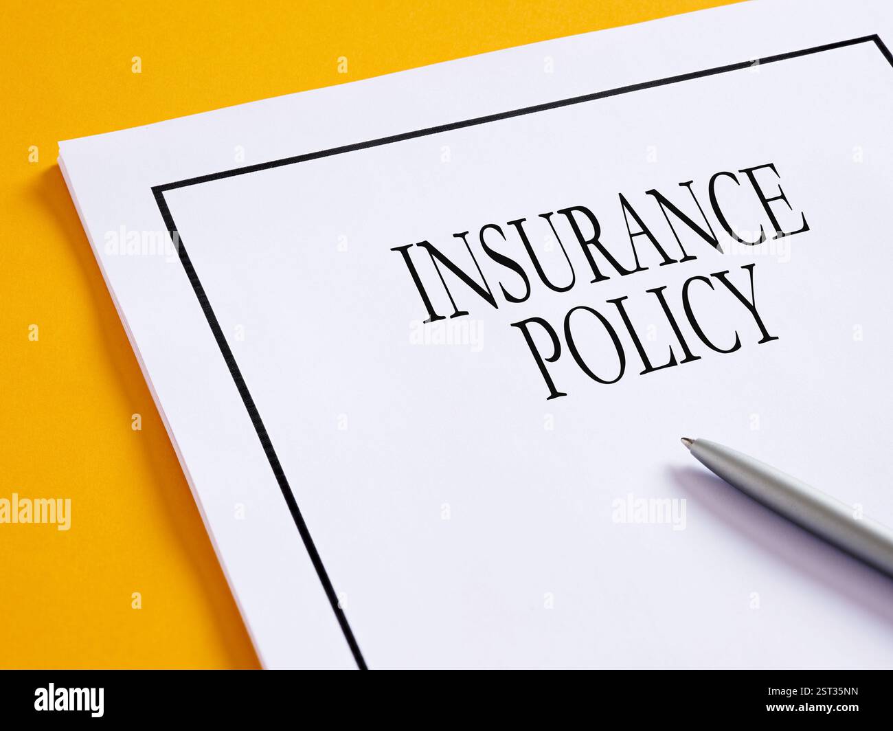 Insurance policy document is sitting on a yellow background with a pen ...