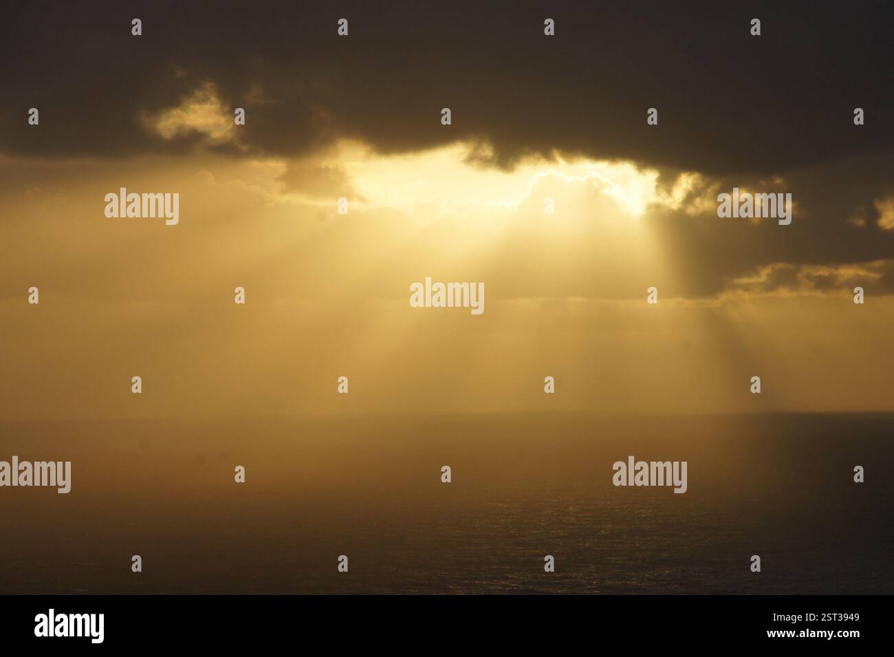 Ocean bathed in golden sunlight. Divine rays pierce through clouds ...