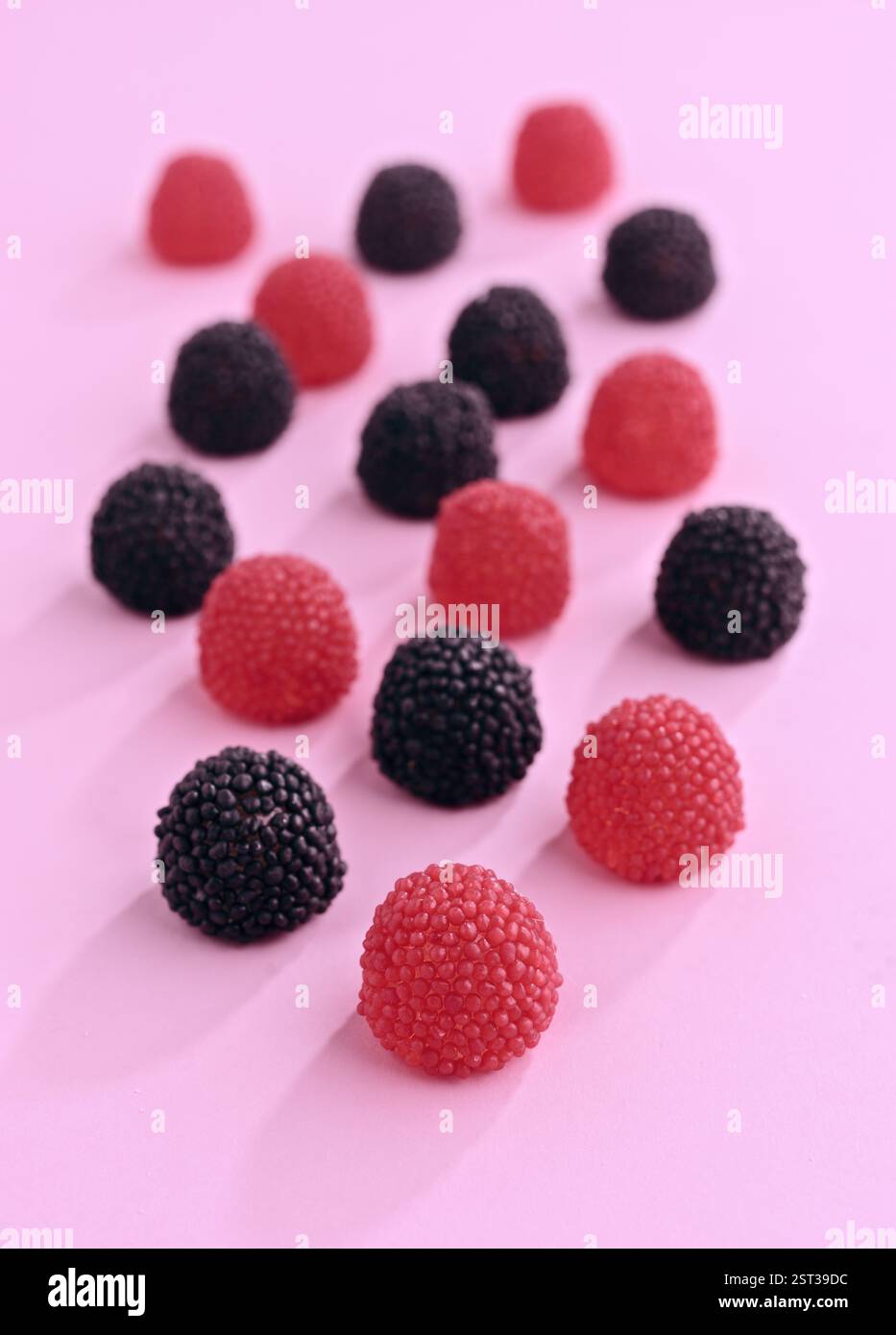 Gummy candies in red and black colors are artistically scattered on a ...