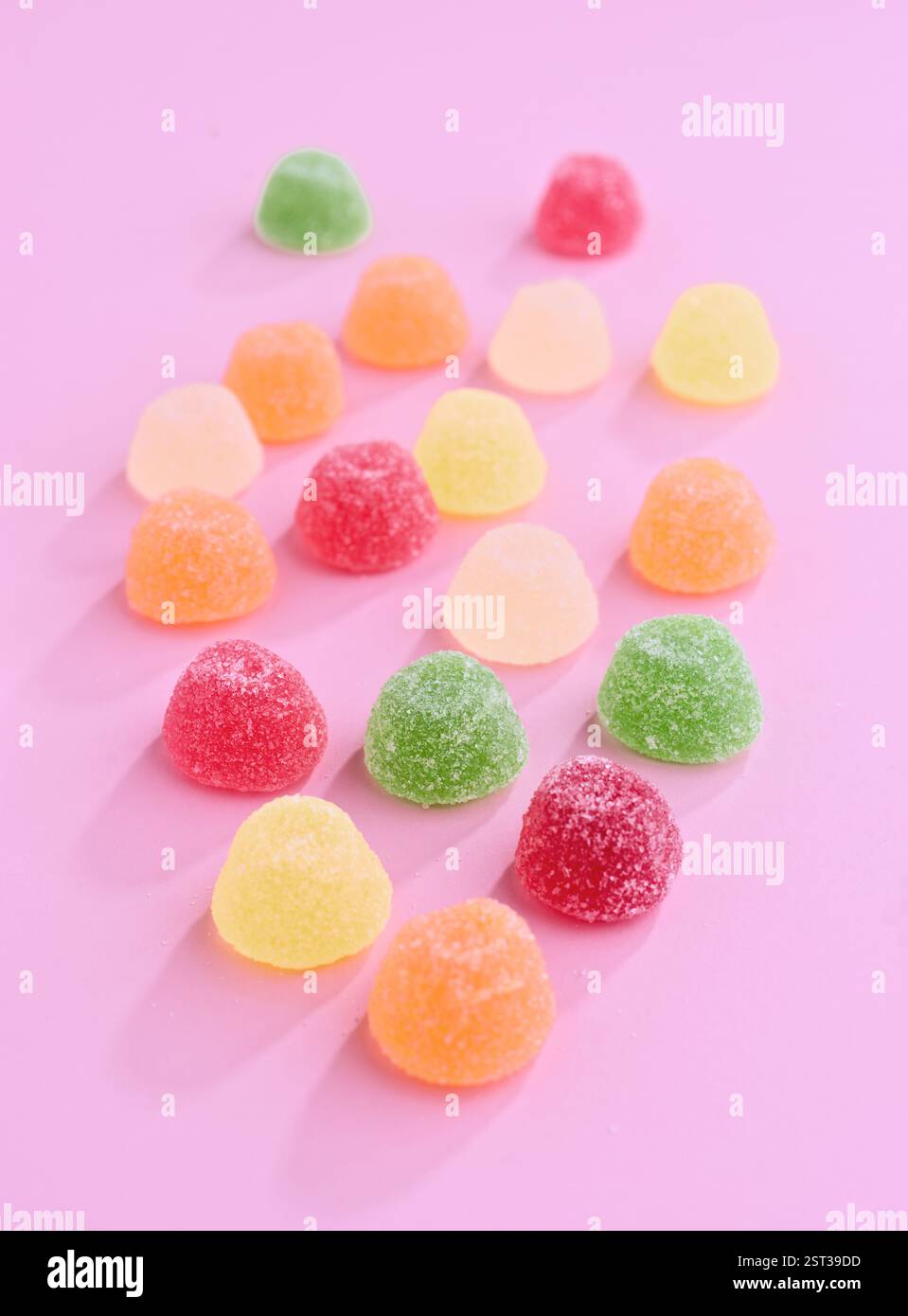 A variety of gummy candies in multiple colors are scattered across a ...