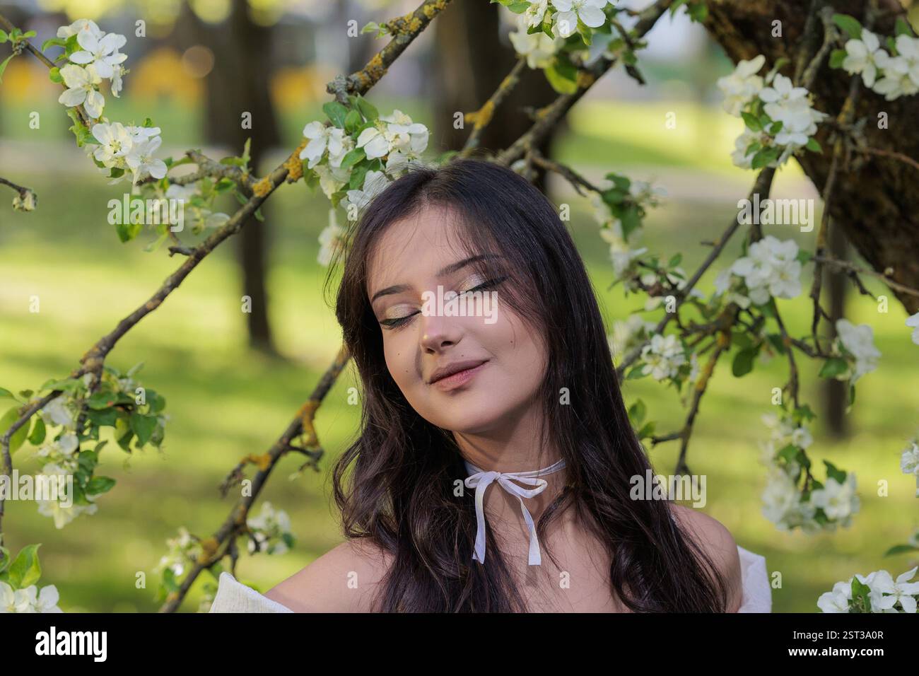 Beautiful Girl with long hair poses near white blossoming apple trees ...