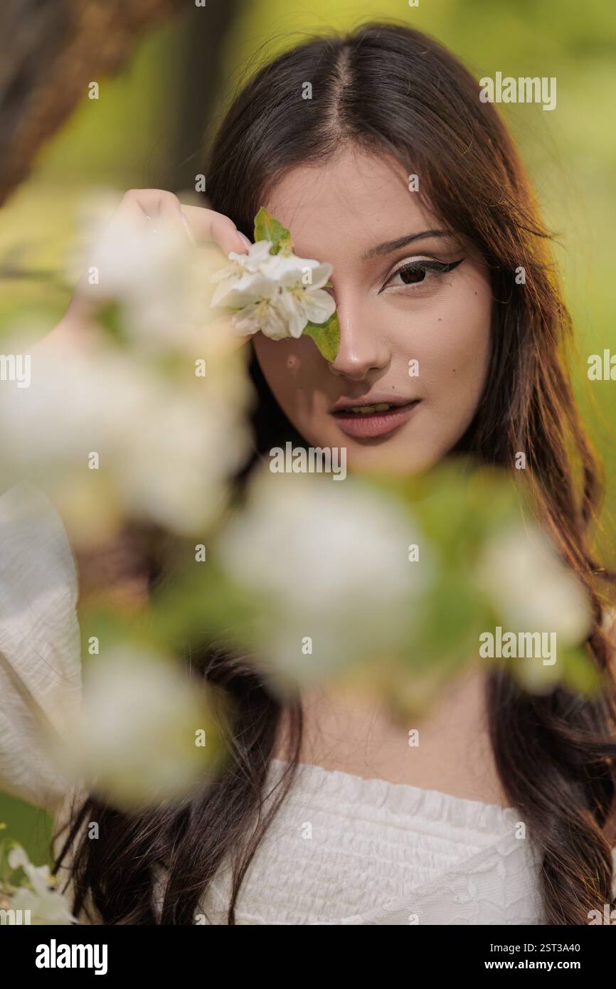 Beautiful Girl with long hair poses near white blossoming apple trees ...