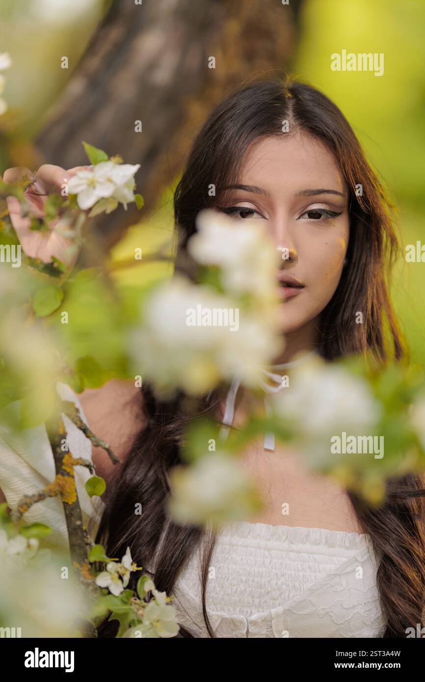 Beautiful Girl with long hair poses near white blossoming apple trees ...