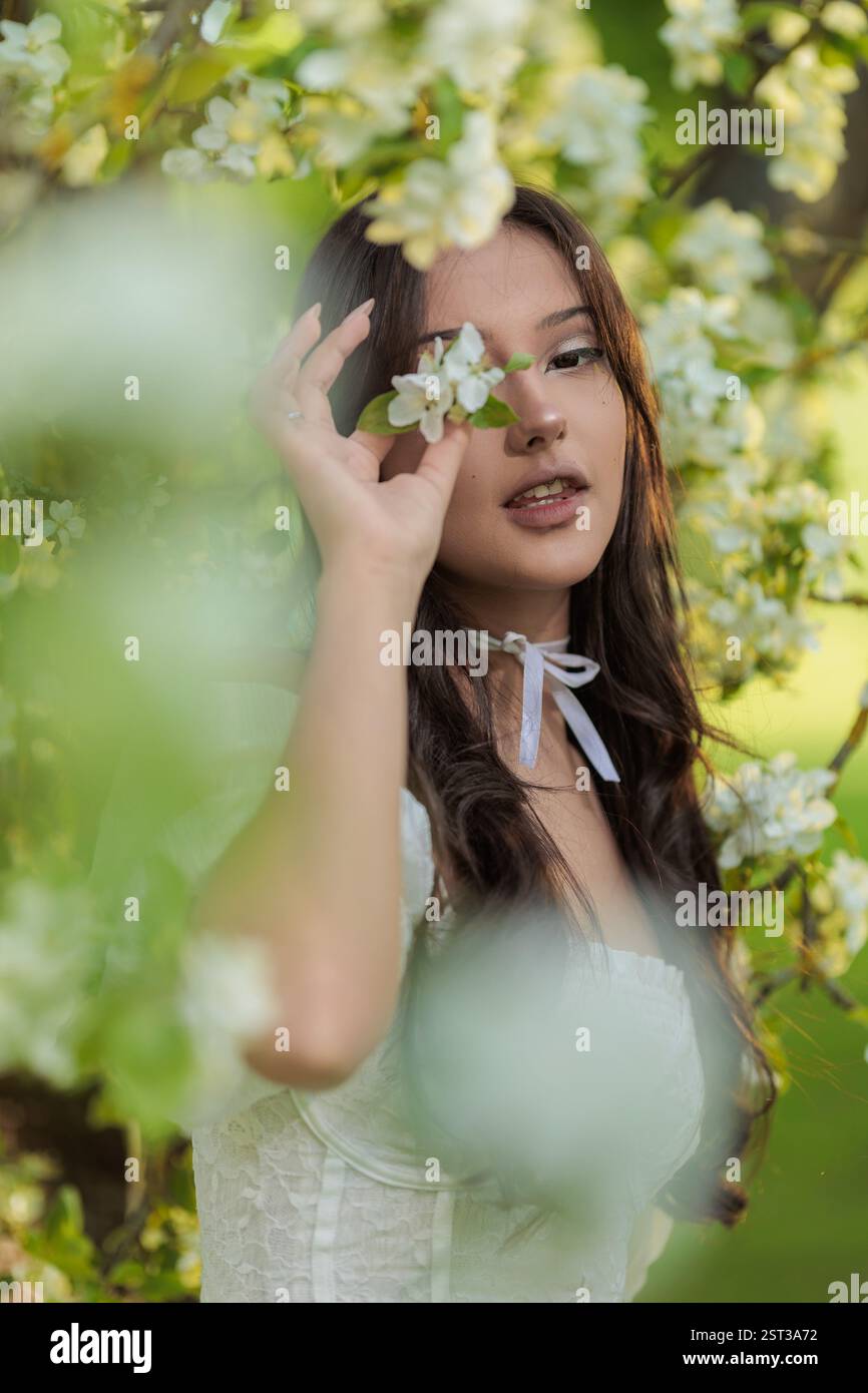 Beautiful Girl with long hair poses near white blossoming apple trees ...