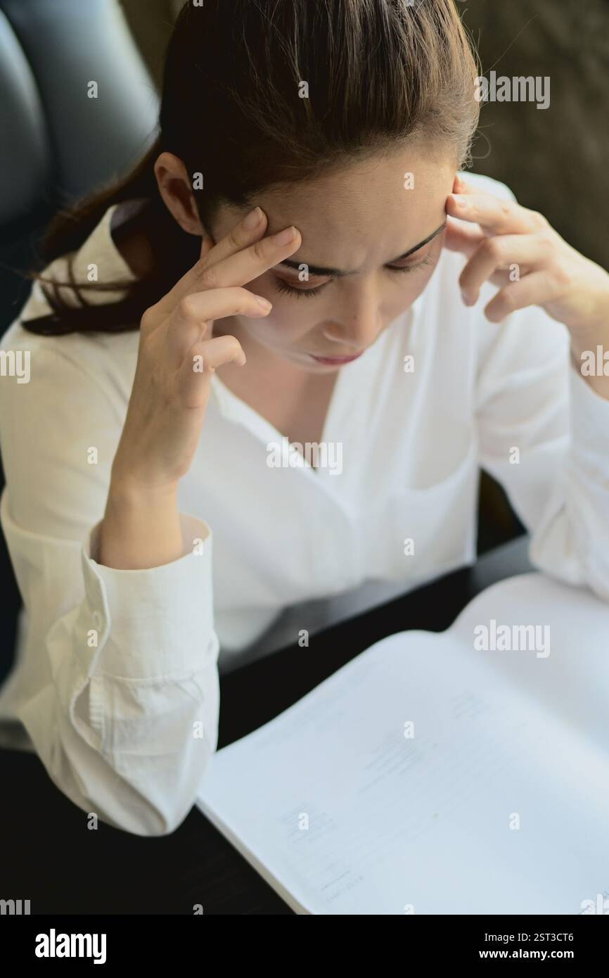 A close-up of a stressed, tired Asian female architect or engineer boss ...