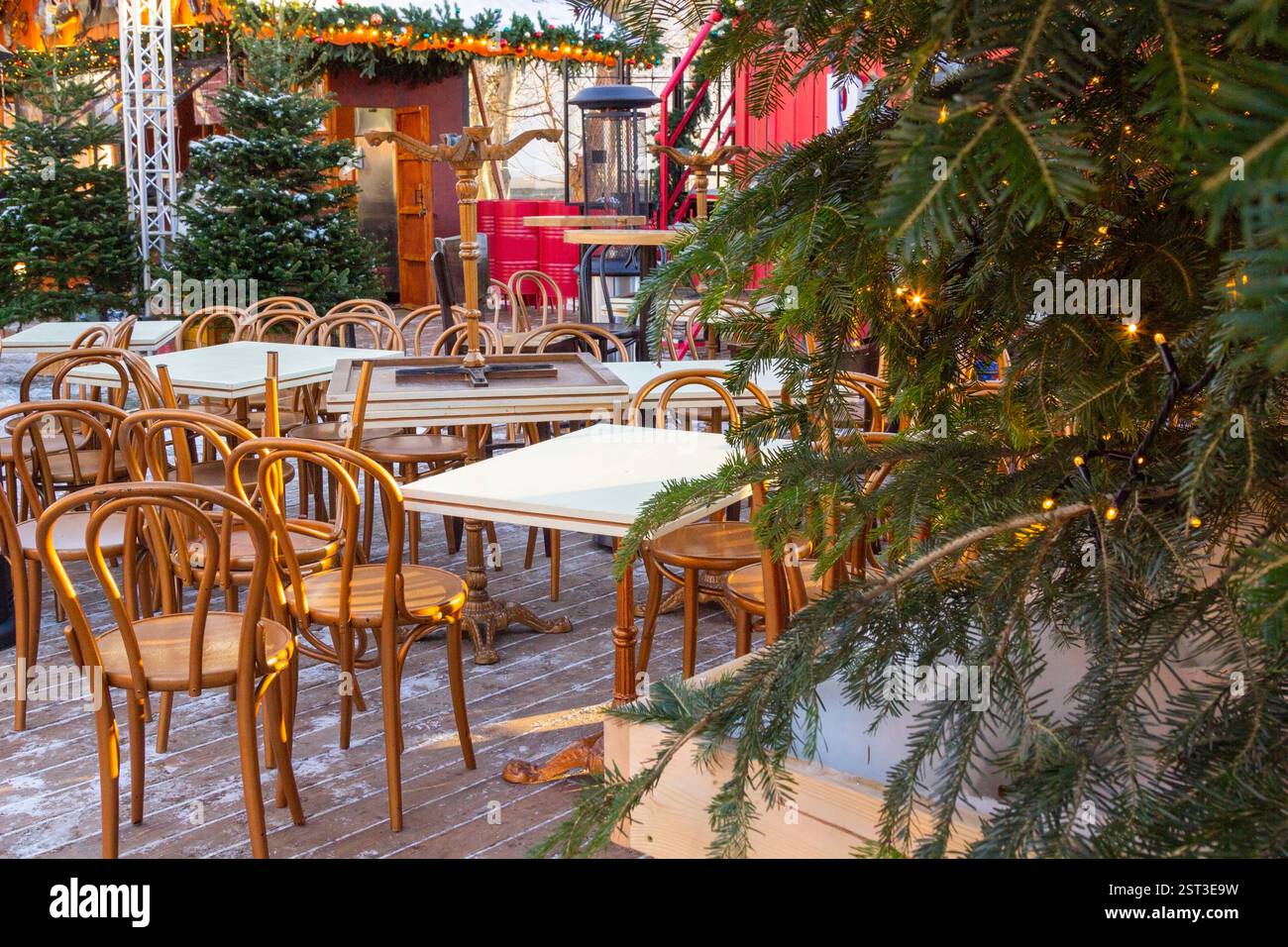 Outdoor terrace of a winter cafe. Empty wooden tables and chairs among ...