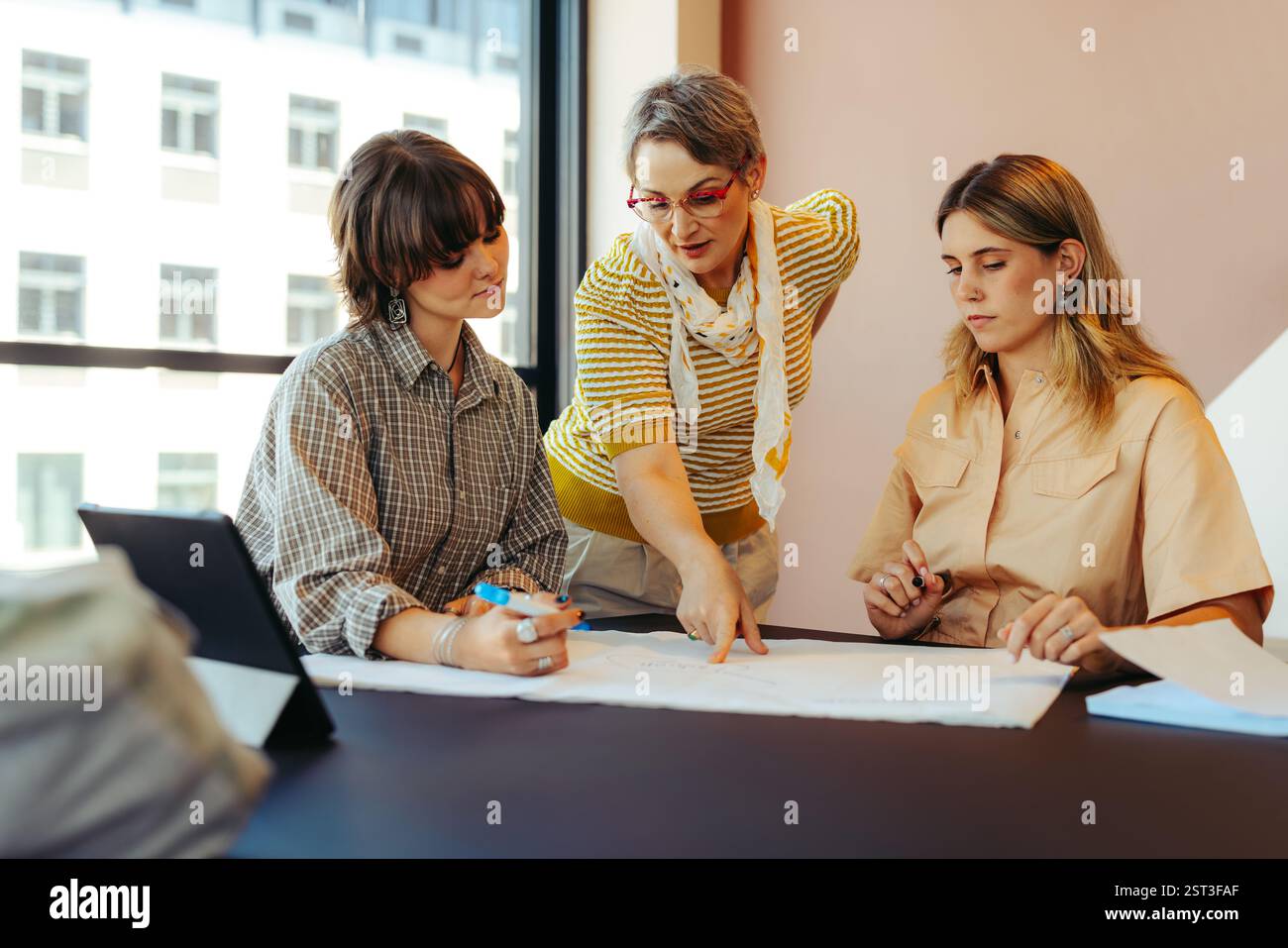 Professor guides college students in a modern classroom, fostering a collaborative environment ...