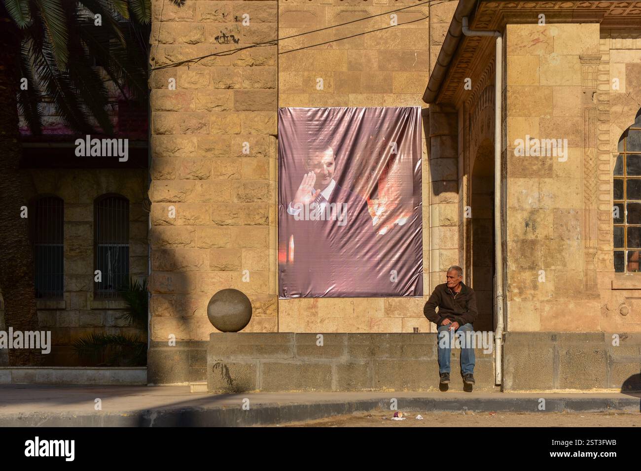 Poster of Bashar al-Assad waving at his subjects next to the main ...