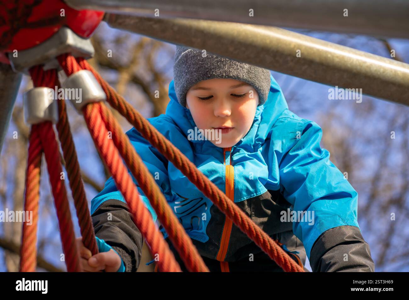 View of a boy climbing ropes on a horizontal bar in a city park Stock ...