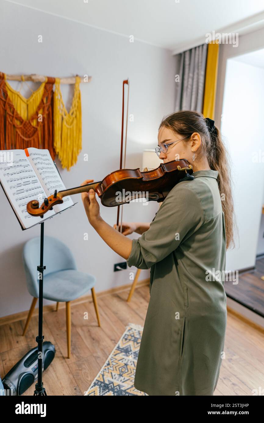 Violin student playing notes at home, preparing for a future ...