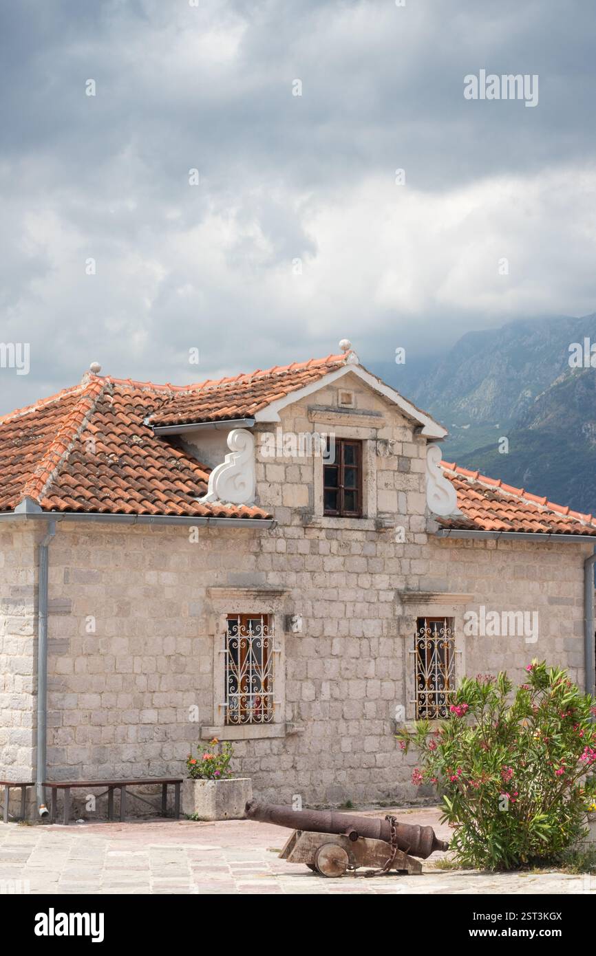 A charming stone building with red tiled roof surrounded by lush ...