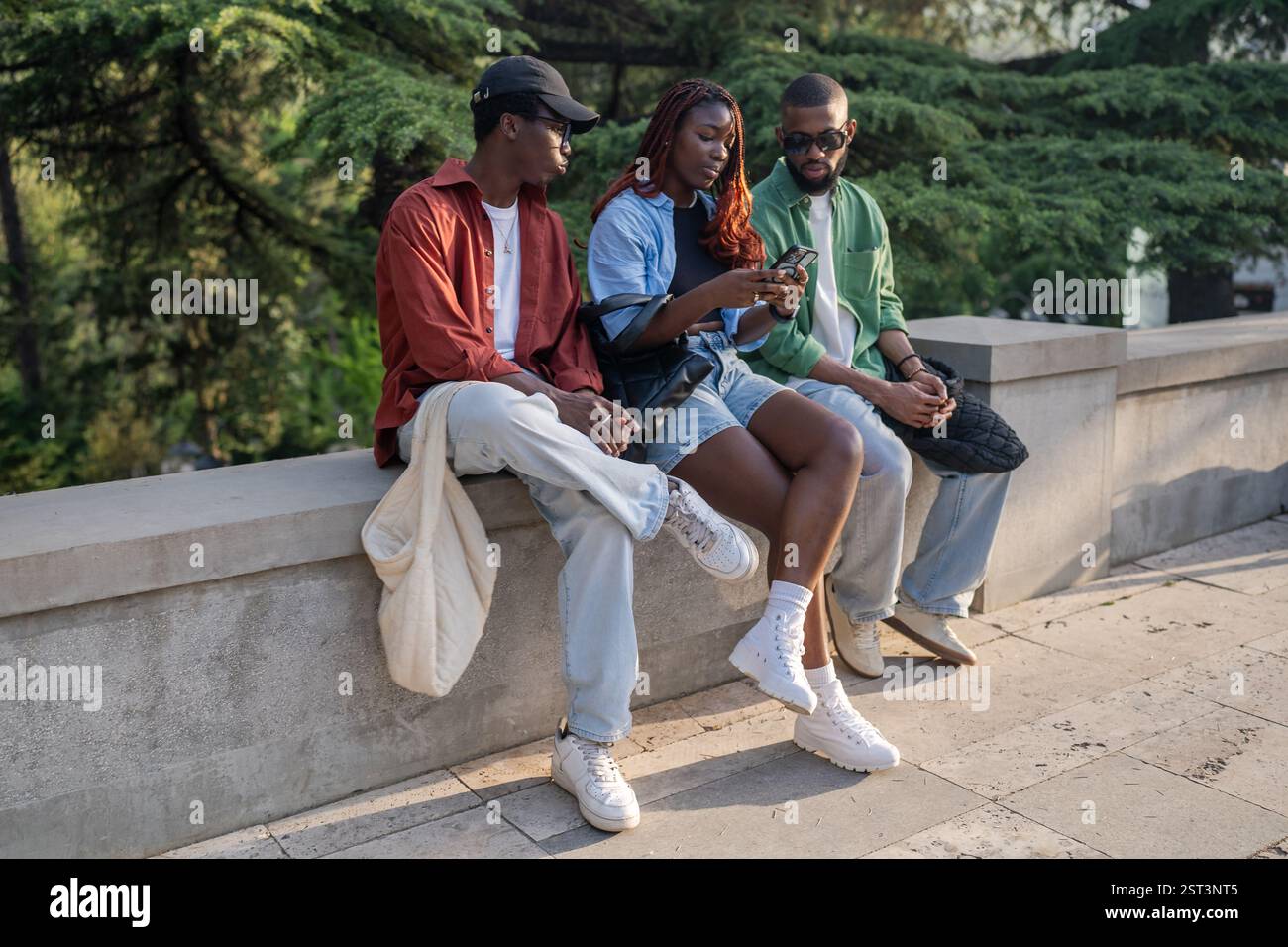 Lively African American friend group in park using smartphone. Woman ...