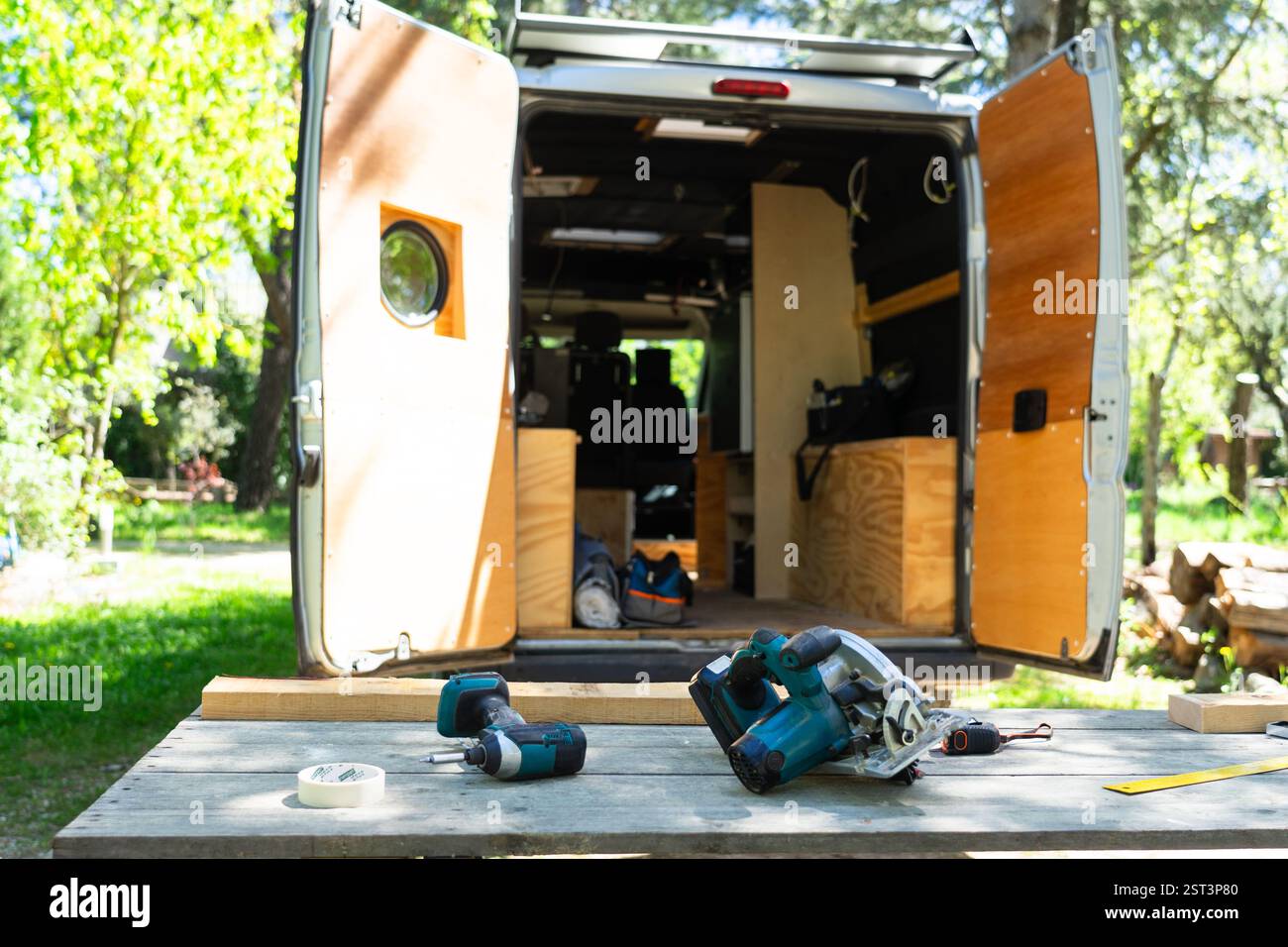 Circular saw and cordless drill resting on workbench with open van in ...