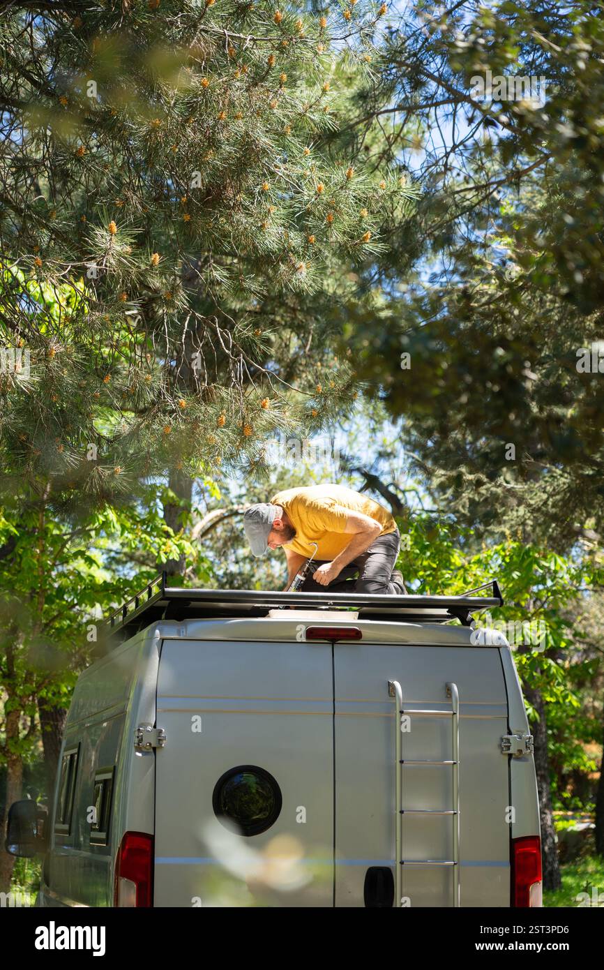 Man working on his camper van roof rack, installing accessories in a ...