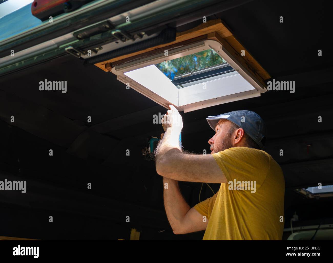 Handyman using a cordless drill while installing a camper van roof ...