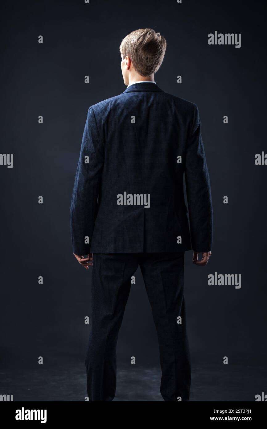 In a dark studio, a man stands confidently in a crisp black suit and ...