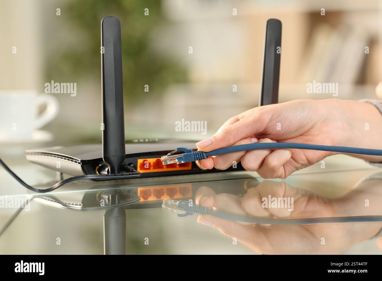 Close up of a woman hand plugging network cable to a modem on a desk at ...
