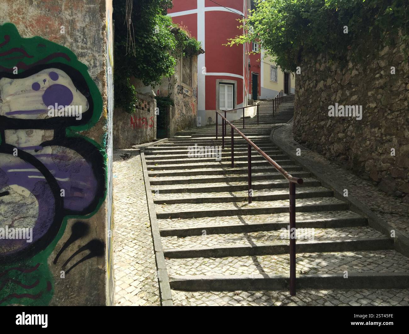 Steep stairs with worn stone steps and metal railings line a narrow ...