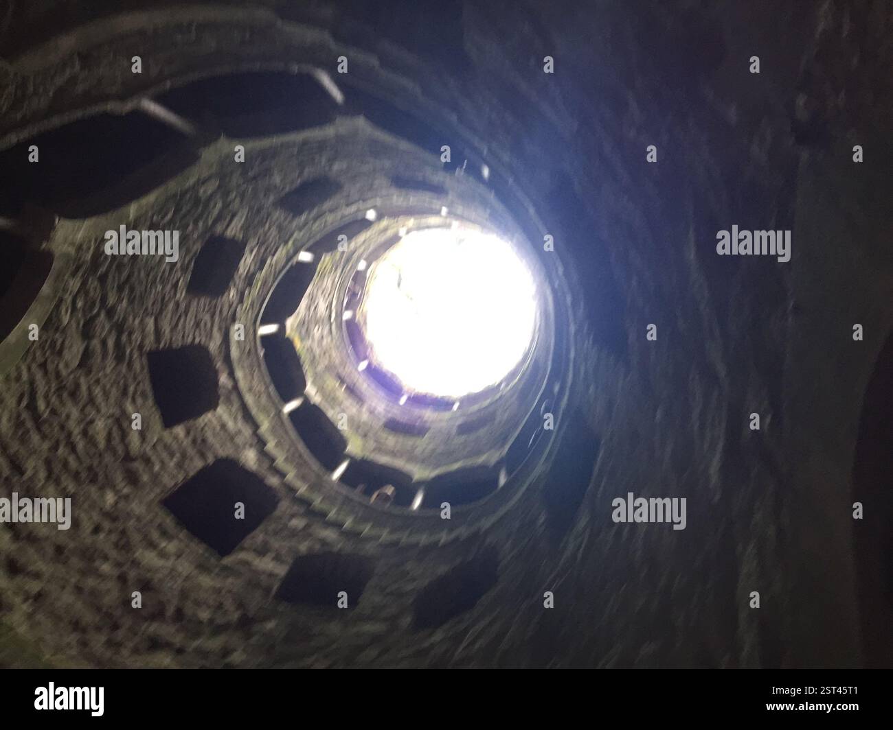 Spiral staircase leads to bright opening. Stone walls and dark shadows ...