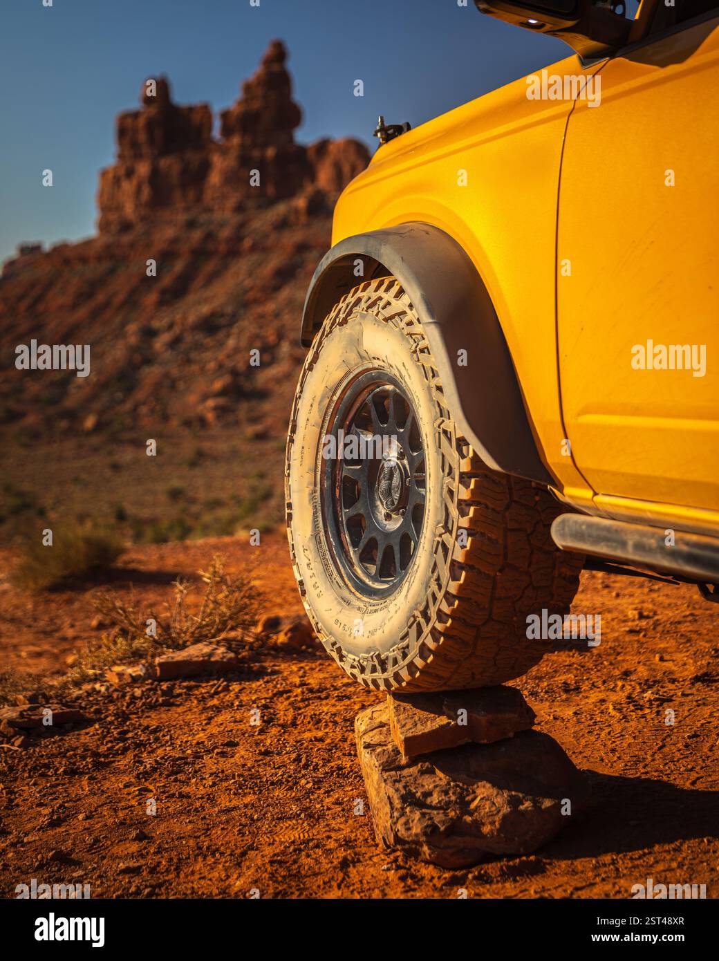 Yellow Truck Off-Road Tire Balanced on Rocks in a Desert Landscape ...