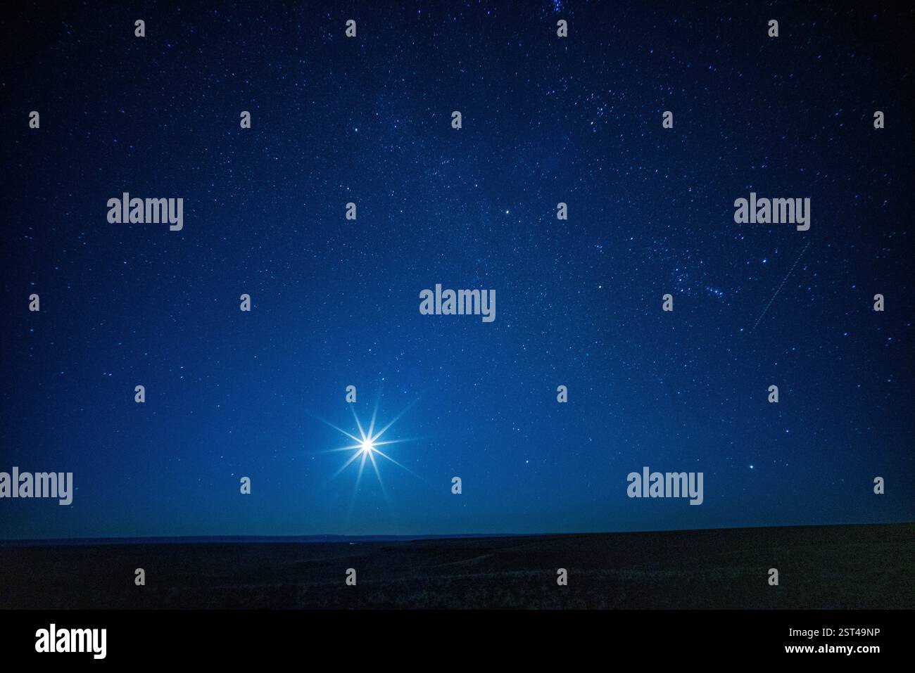 A starburst effect of the moon just above the horizon in the night sky ...