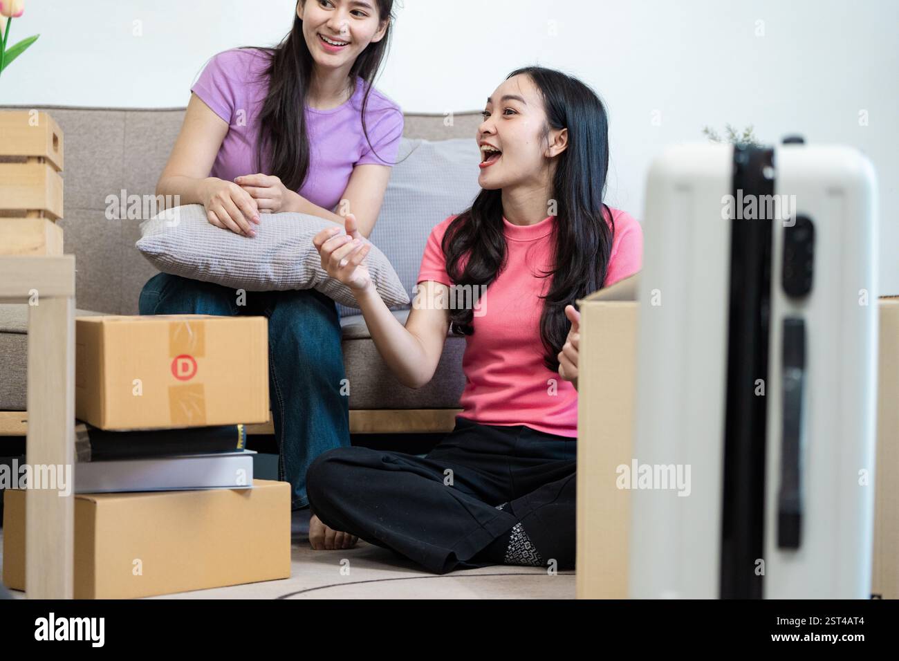 Joyful LGBTQIA couple playing together in a cozy living room, unboxing ...