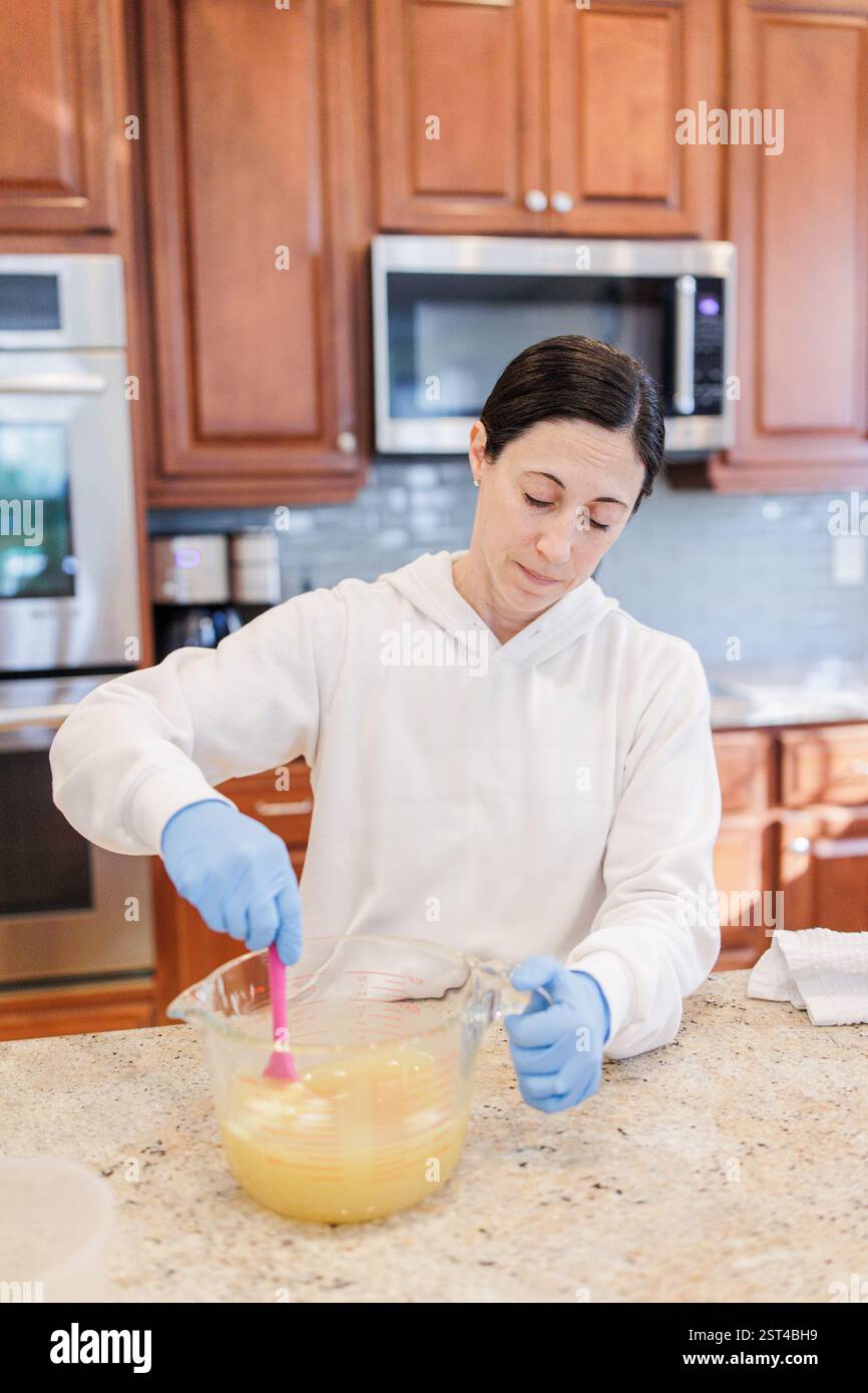Woman stirring melted cocoa butter and lye for soap making in Stow ...