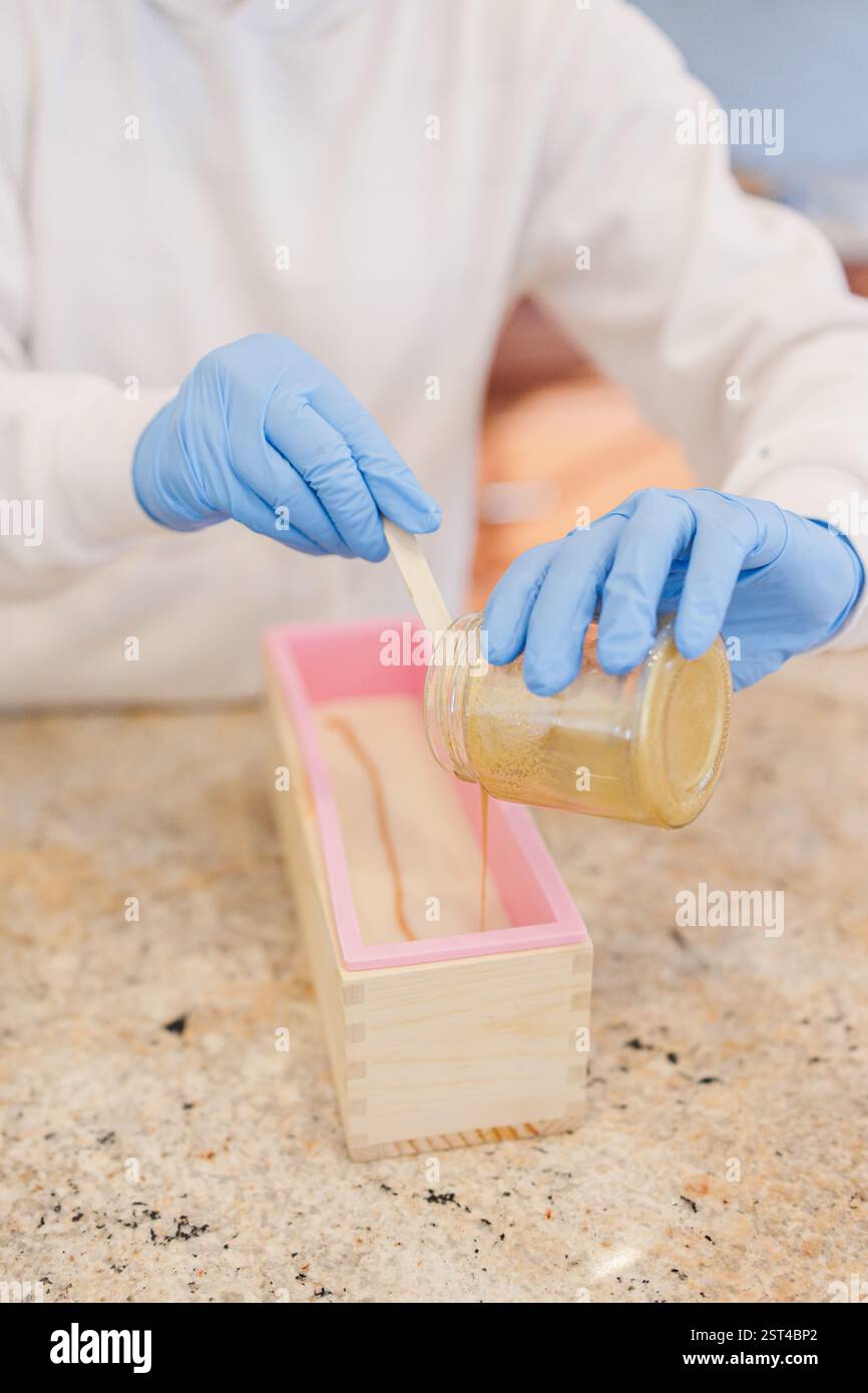 Woman adding gold mica swirl to handmade soap in mold in Stow Stock ...