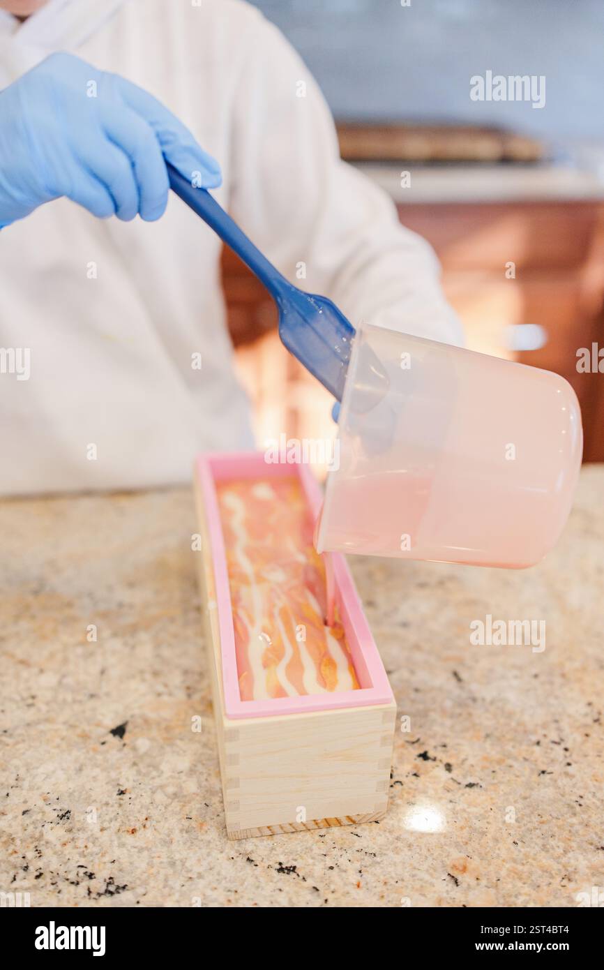 Woman pouring final soap layer over gold mica swirl in mold in Stow ...