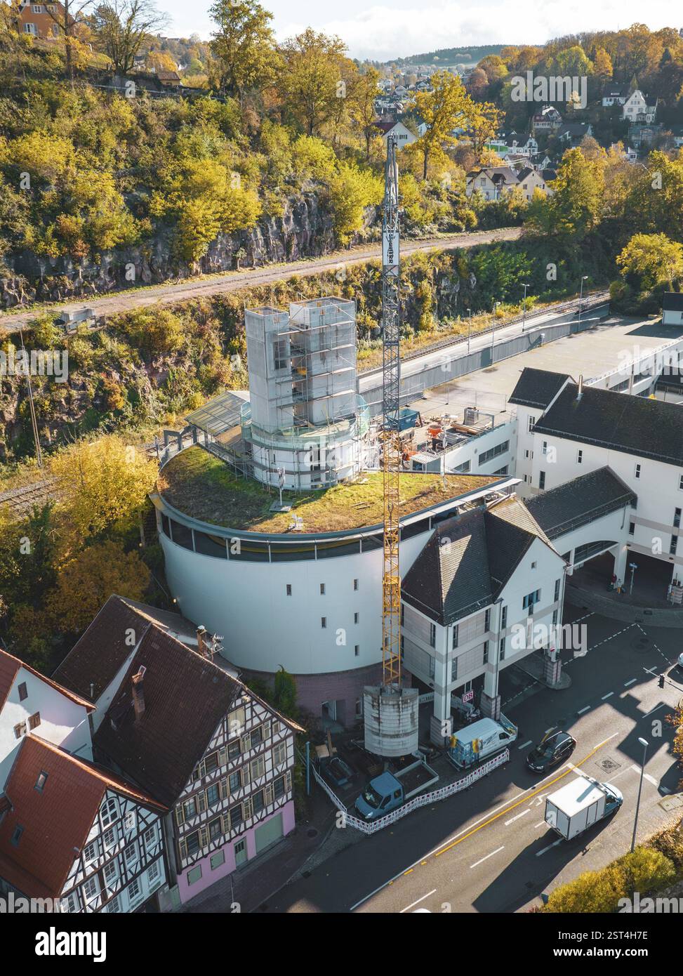 Aerial view of a round building with green roof and crane working above ...
