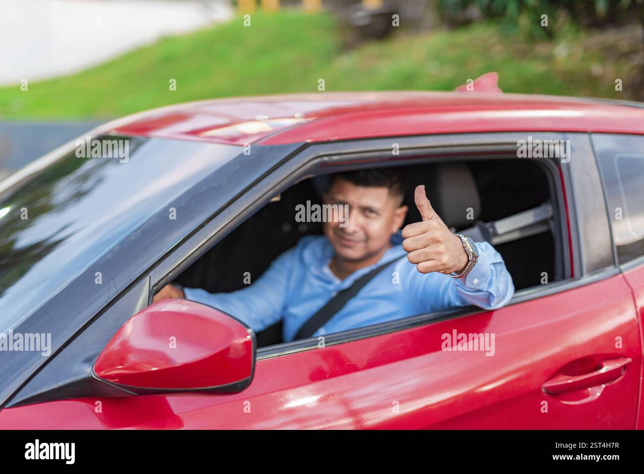 Smiling driver in his car giving a thumbs up. Male driver showing ...