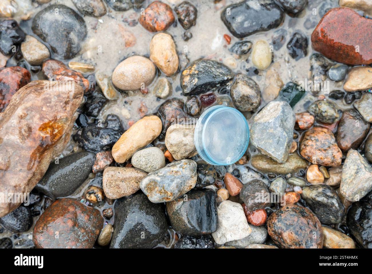 Small plastic cap lies among pebbles on beach, highlighting ocean ...