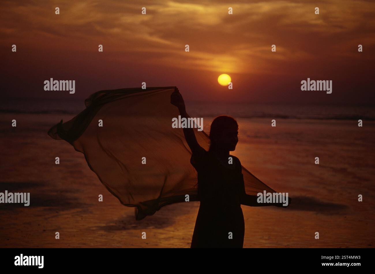 Lady in silhouette flying sari in air at beach Stock Photo - Alamy