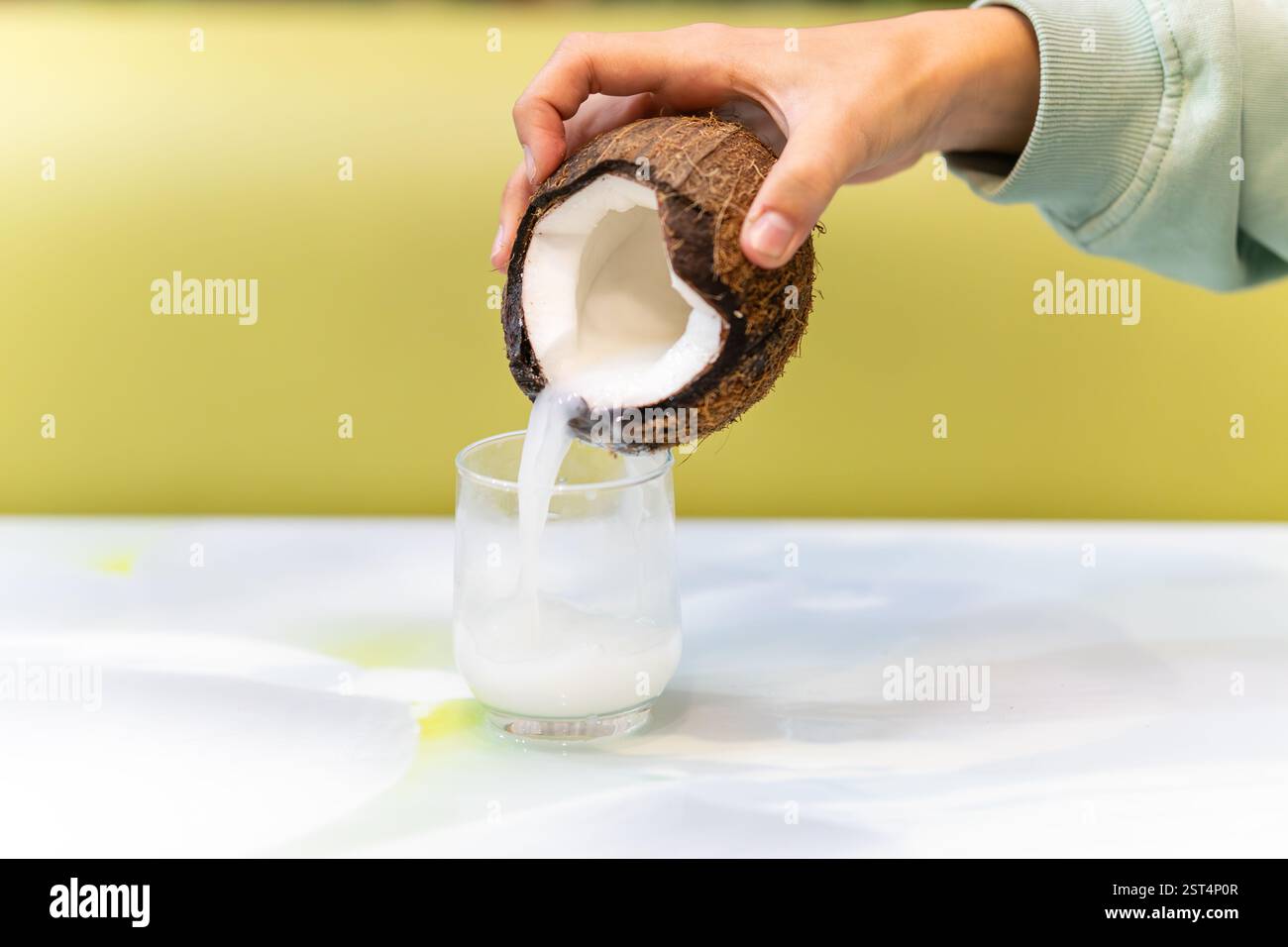 An image of coconut milk. Female hand pouring coconut milk from coconut ...