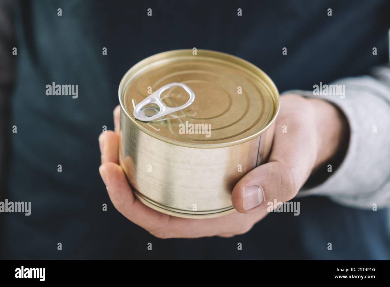 opening a tin can. Tin can with ring in male hand. Close up an empty ...