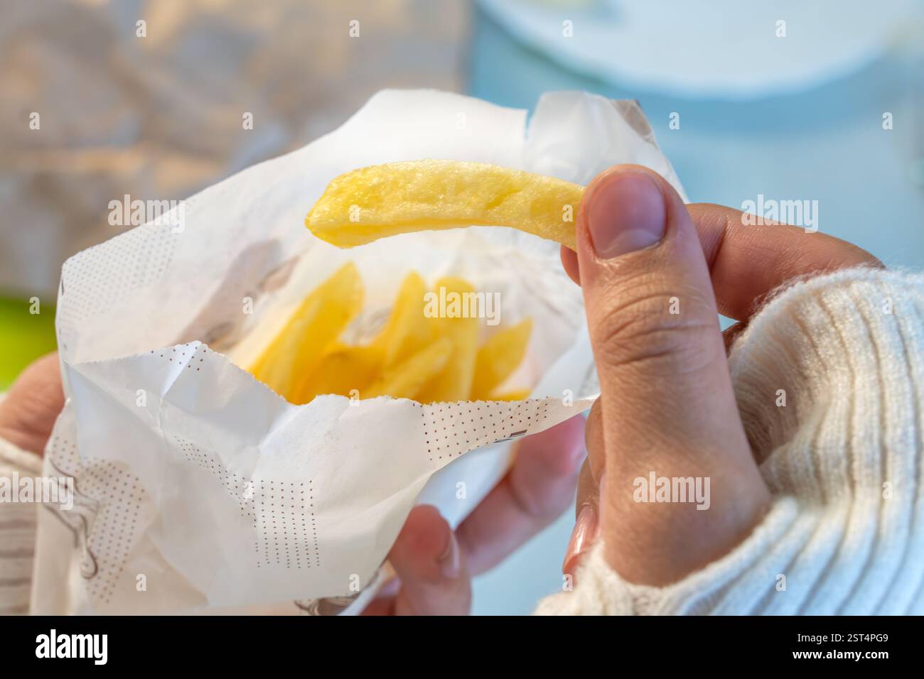 anonymous woman enjoy eating french fries in restaurant. hand holds ...