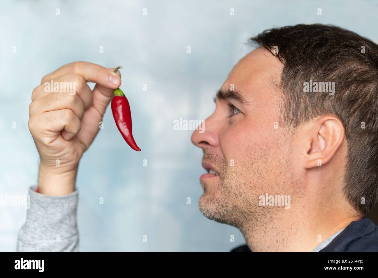 ridiculous expression of man with hot chillies in his hand. a man is ...