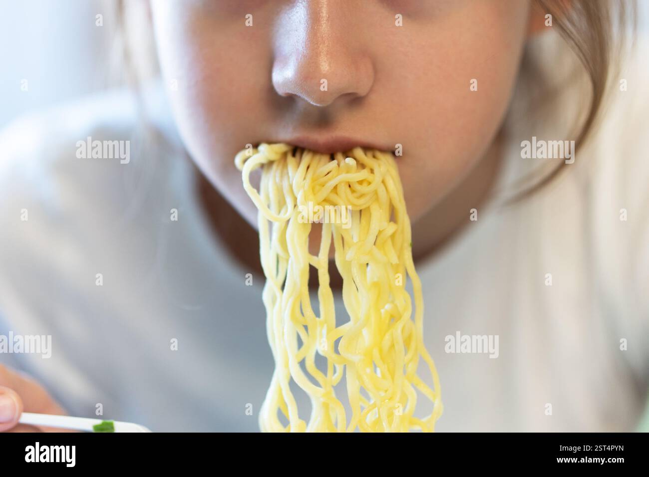 Cute asian child girl eating delicious instant noodles with fork ...