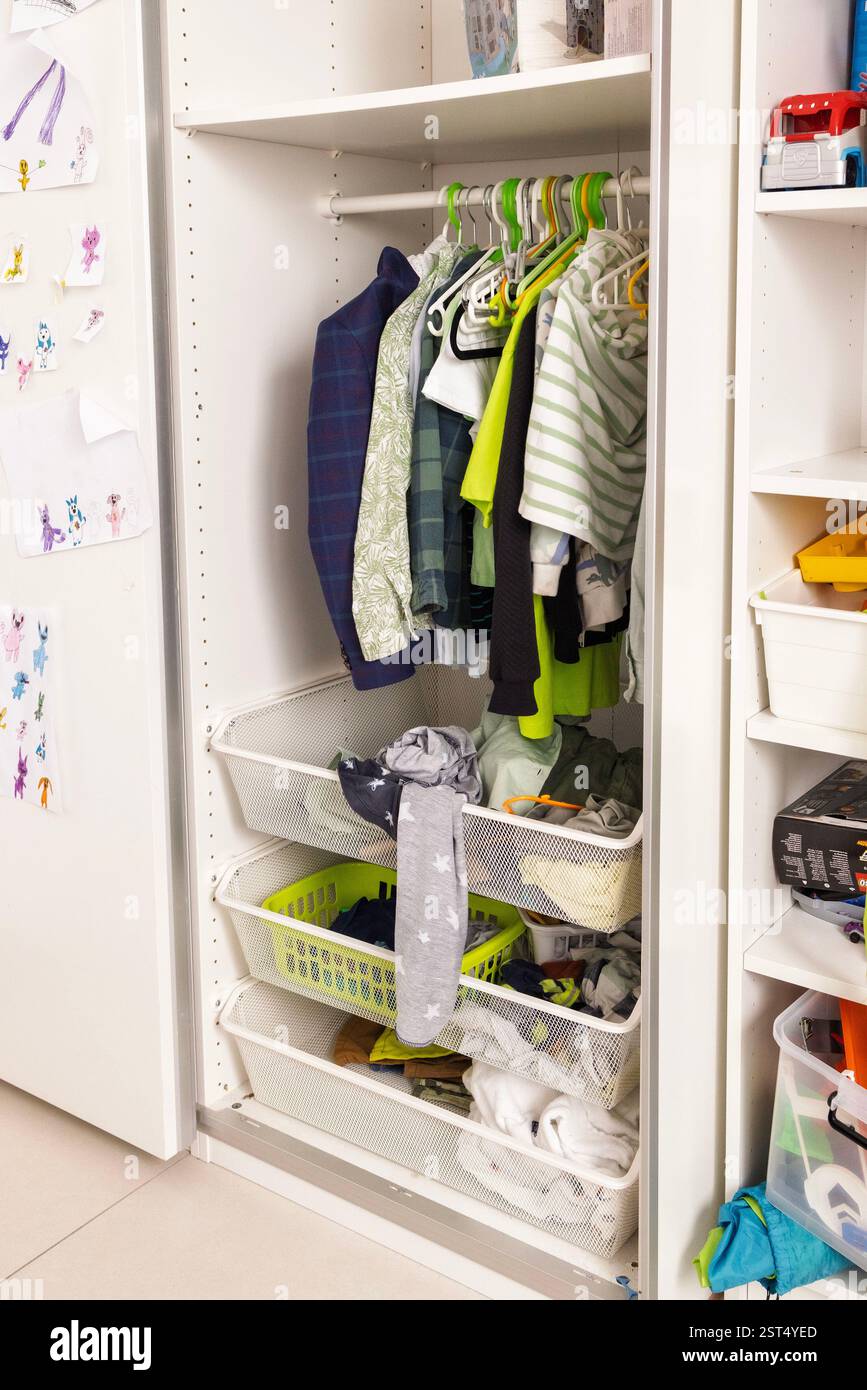 Organized boy's wardrobe with clothes on hangers and mesh baskets for ...